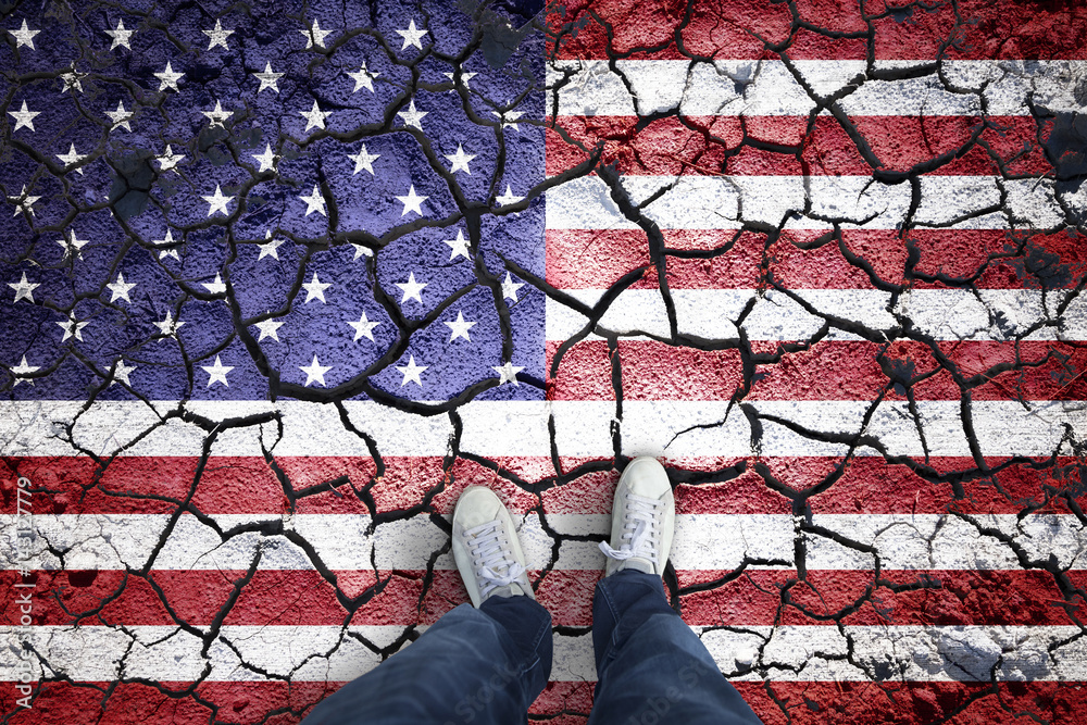 Top view of a man standing on cracked soil with torn United States of ...