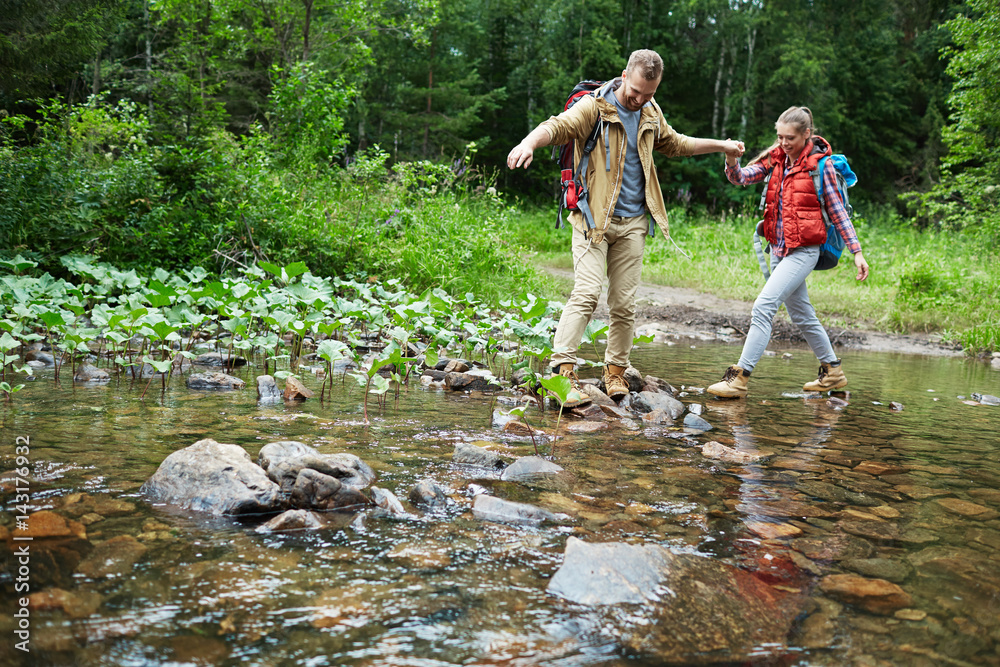 Adventurous couple crossing river by stepping stones Stock Photo ...