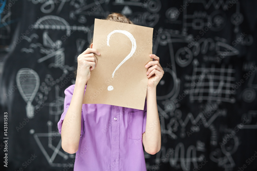 Schoolboy hiding his face behind paper with question mark Stock Photo ...