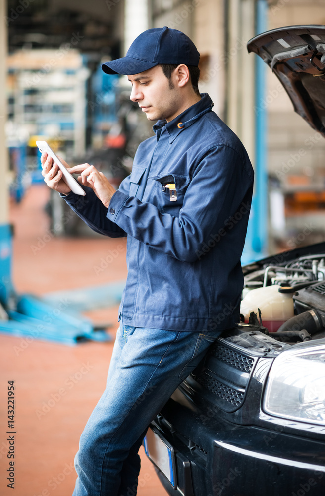 Mechanic using a tablet in his garage Stock Photo | Adobe Stock