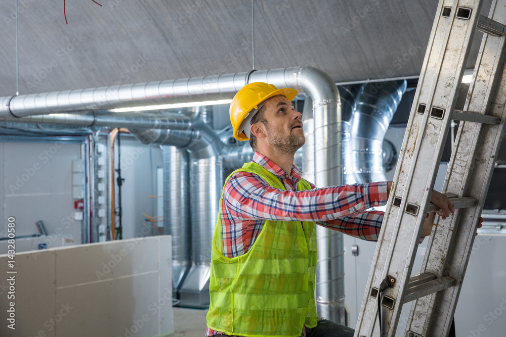 Worker making final touches to HVAC system. HVAC system stands for ...