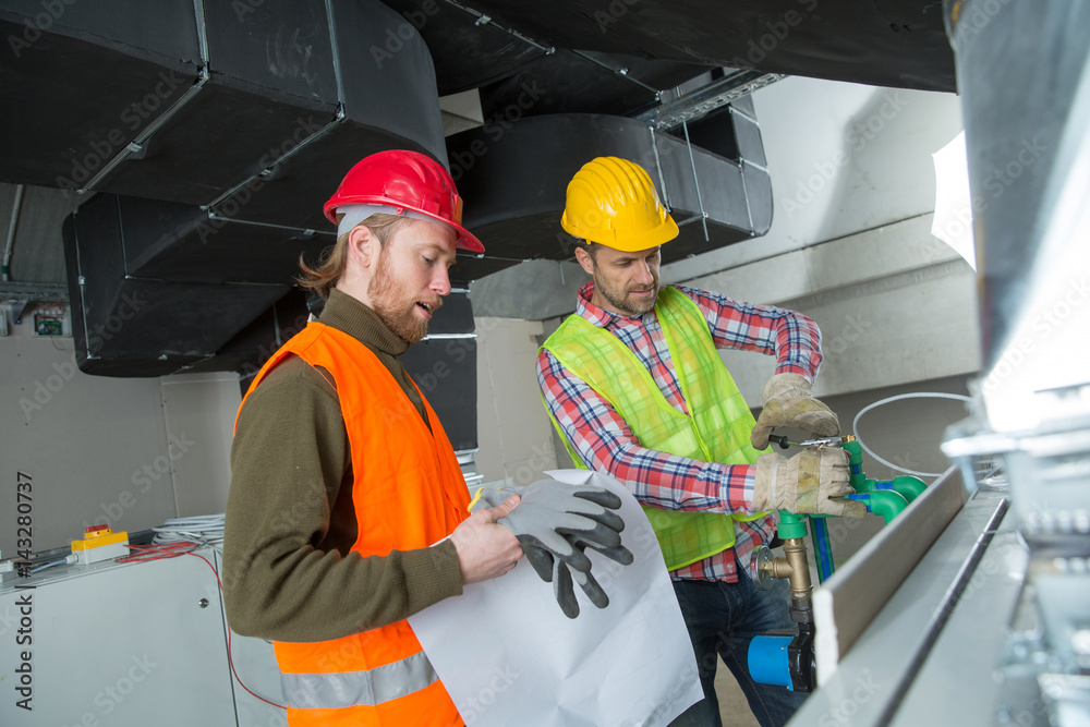 Workers making final touches to HVAC system. HVAC system stands for ...