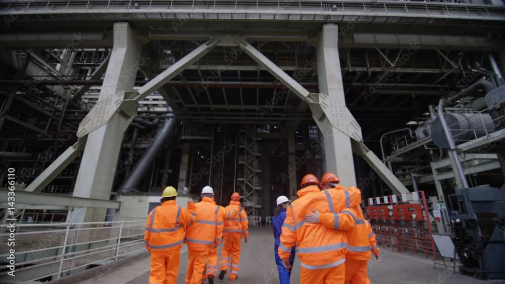 Team of engineers in power station, wide shot of workers & building ...