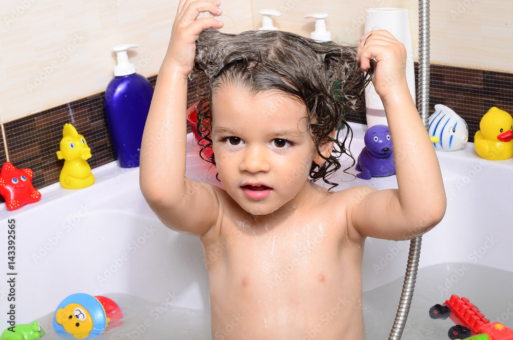 Beautiful toddler taking a bath in a bathtub with bubbles. Cute kid ...