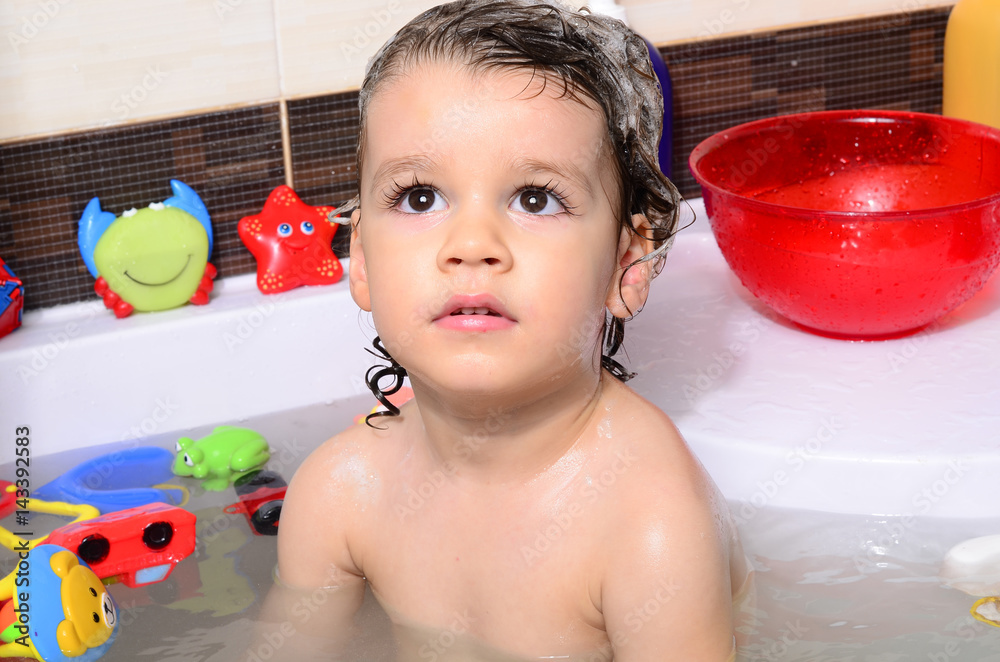 Beautiful toddler taking a bath in a bathtub with bubbles. Cute kid ...