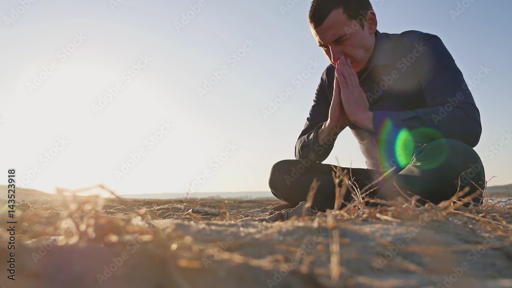 religion. Man praying sitting on the ground at sunset sun silhouette ...