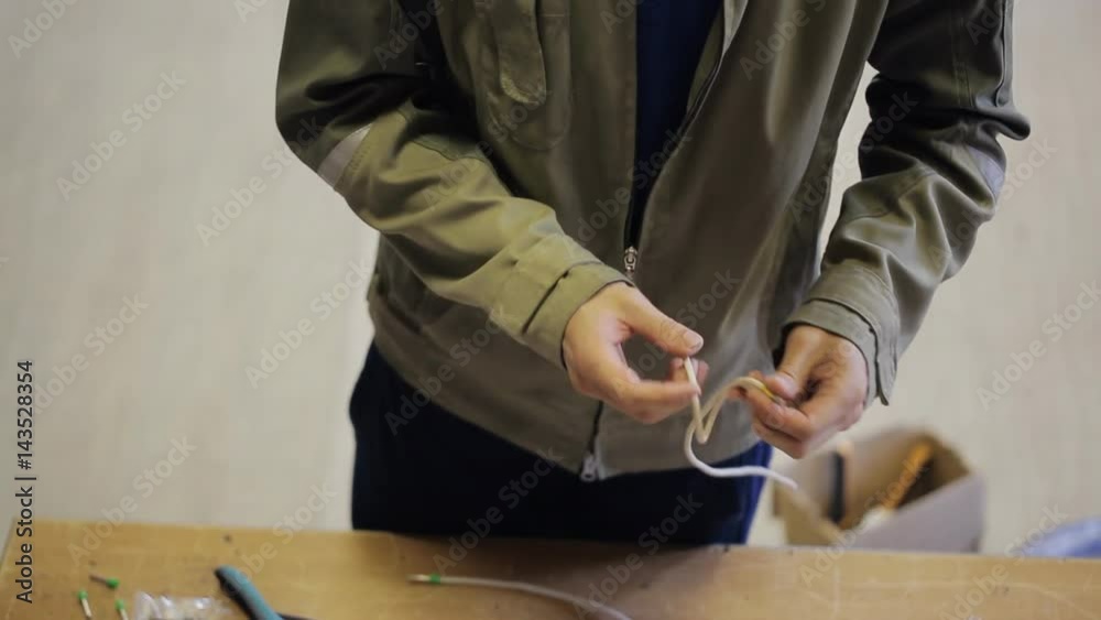Stockvideon Man at the desk prepares white wires for connection of ...