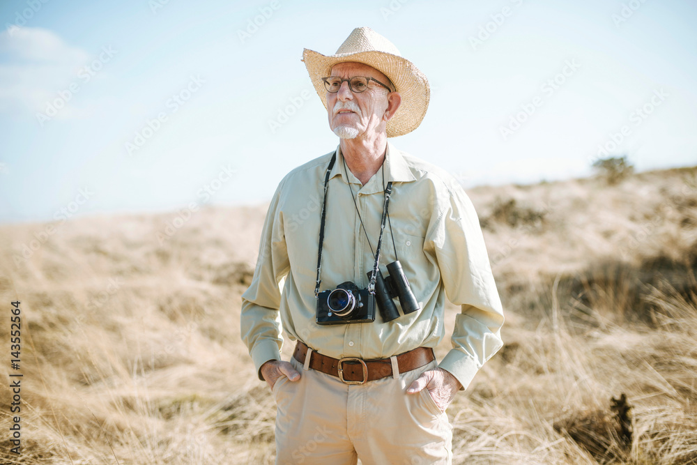 Senior safari man with camera and binocular in field. 스톡 사진 | Adobe Stock