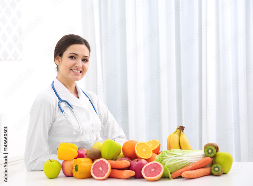 Female nutritionist with different fruits and vegetables at desk Stock ...