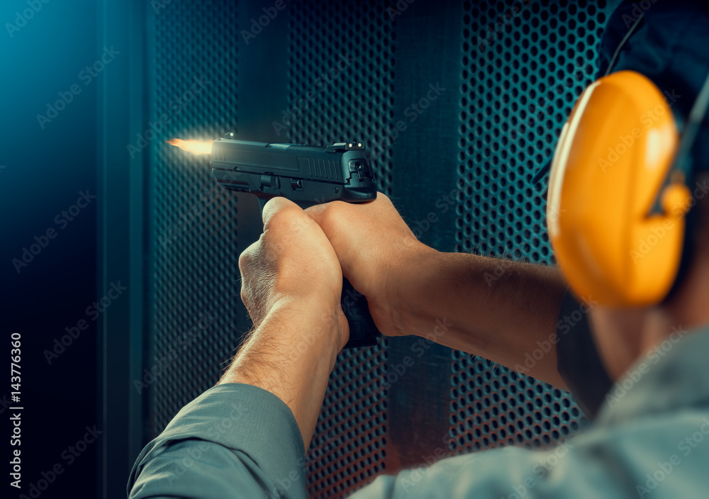 man firing pistol at target indoor shooting range Stock Photo | Adobe Stock