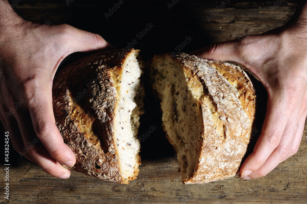 male hands breaking a loaf of bread like a symbol of Christian religion ...