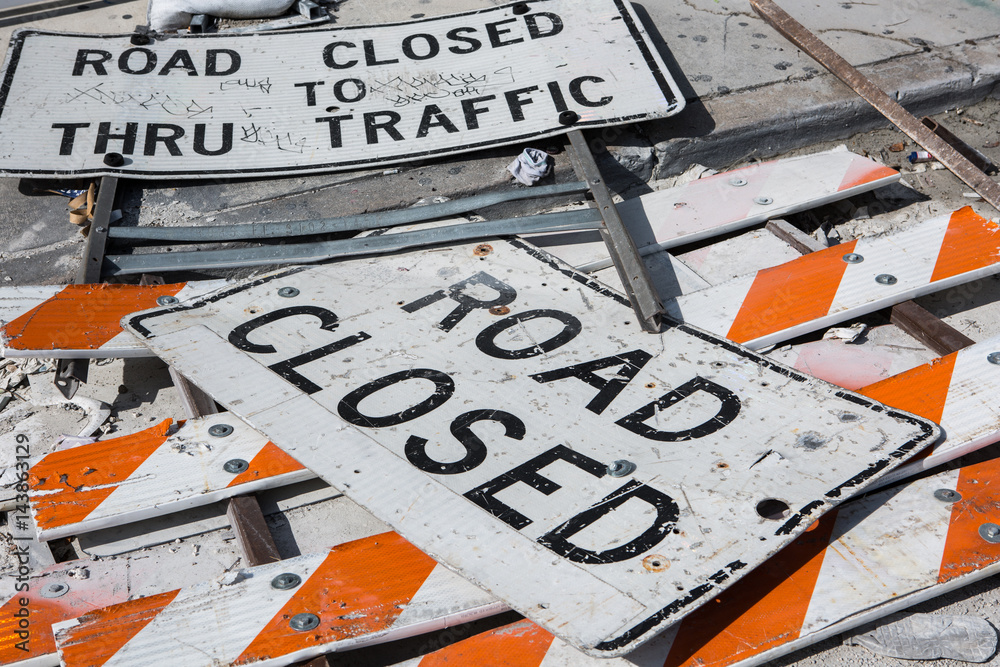 Road Closed Signs fell down on a road with broken barricades like a ...
