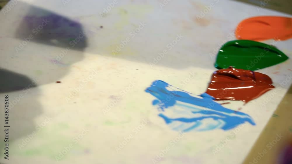 Oil paint spread from the glass can on the palette. Painter's hands ...