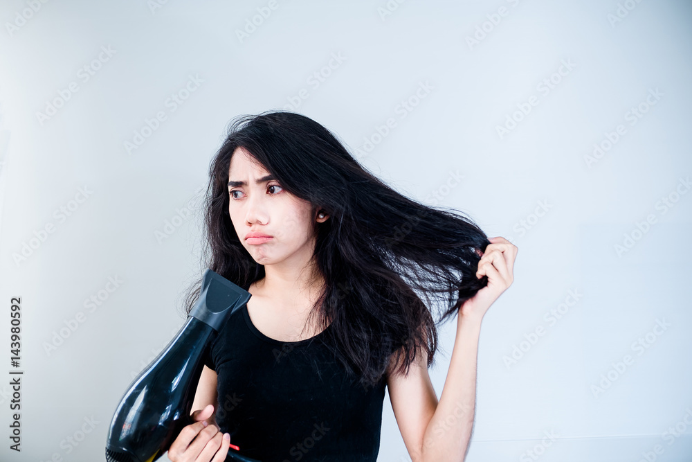 Young Asian woman in Damaged long black hair looking at split ends on a ...