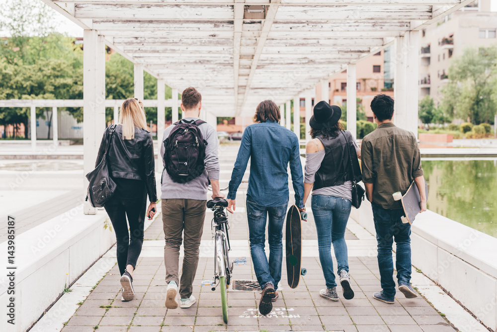Back view of group of friends multiethnic millennials walking outdoor ...