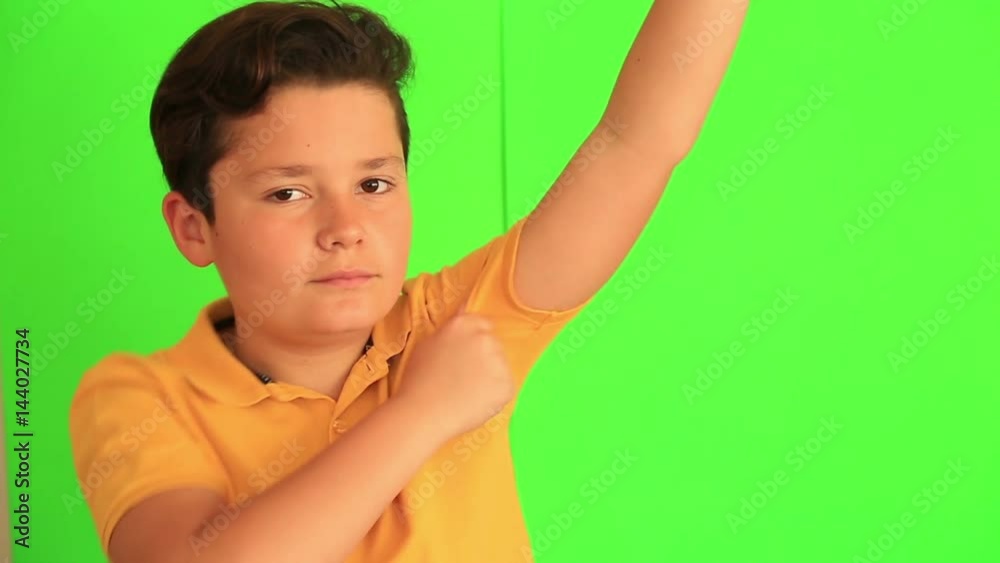 Young boy showing his strong arms against chroma key green screen ...