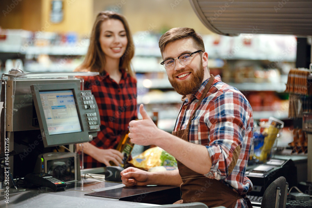 Foto de Happy cashier man on workspace in supermarket do Stock | Adobe ...