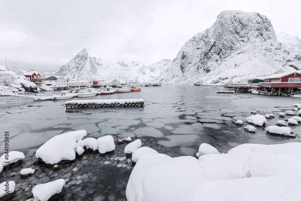 Icy sea and snowy peaks around the typical houses called rorbu and ...