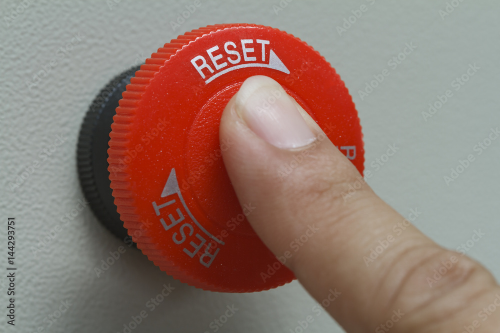 Finger touch on red emergency stop switch button on control panel for ...