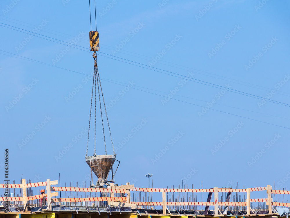 Lifting crane delivers concrete bucket to construction site to place of ...
