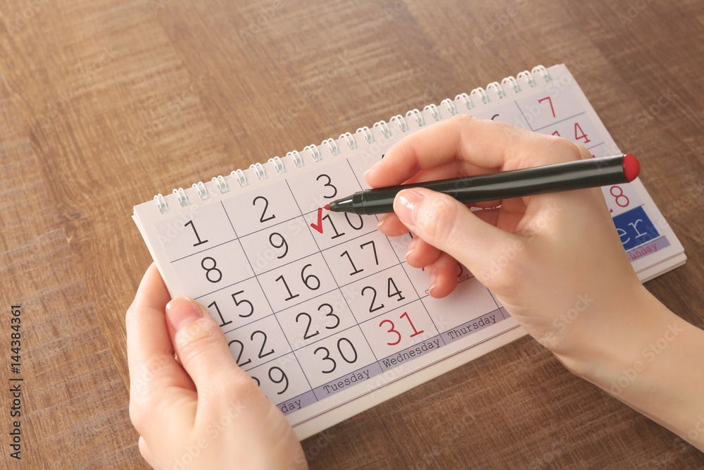 Female hands painting check mark in calendar on wooden background Stock ...