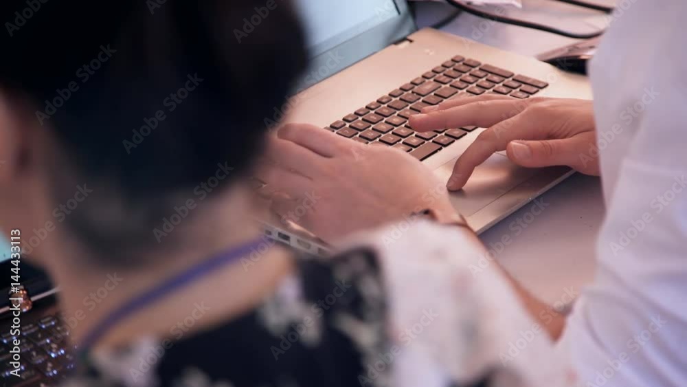 Shooting from back women on woman who working on laptop in office ...