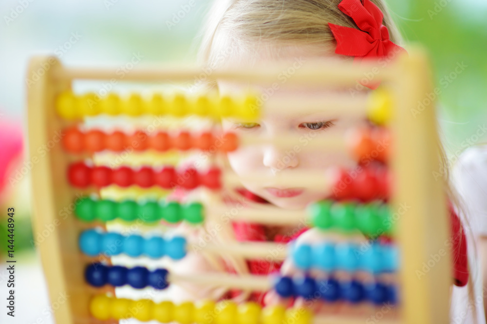 Cute little girl playing with abacus at home. Smart child learning to ...