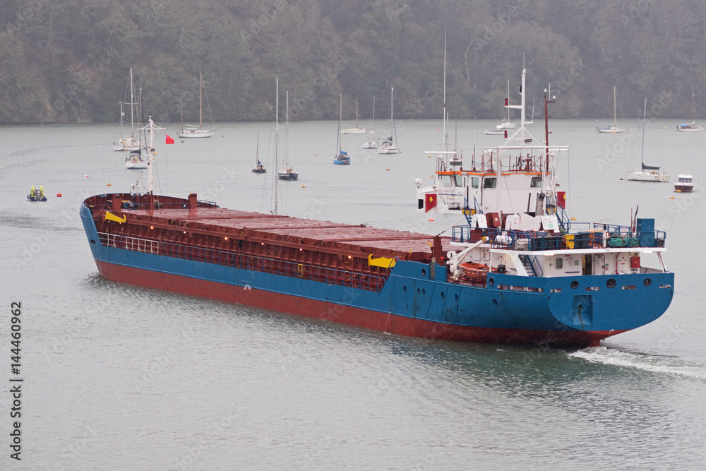 Cargo ship making its way in heavy rain up the Truro river near Malpas ...