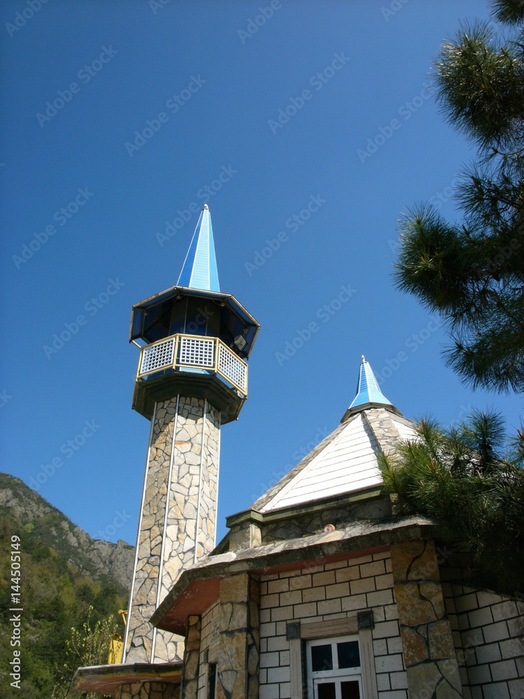 Schöne kleine Moschee aus Naturstein mit Minarett vor strahlend blauem ...