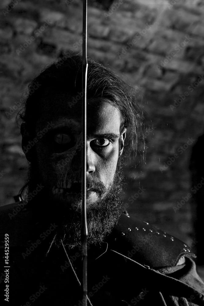 Portrait of a man with huge beard close up. He is holding a sword near ...