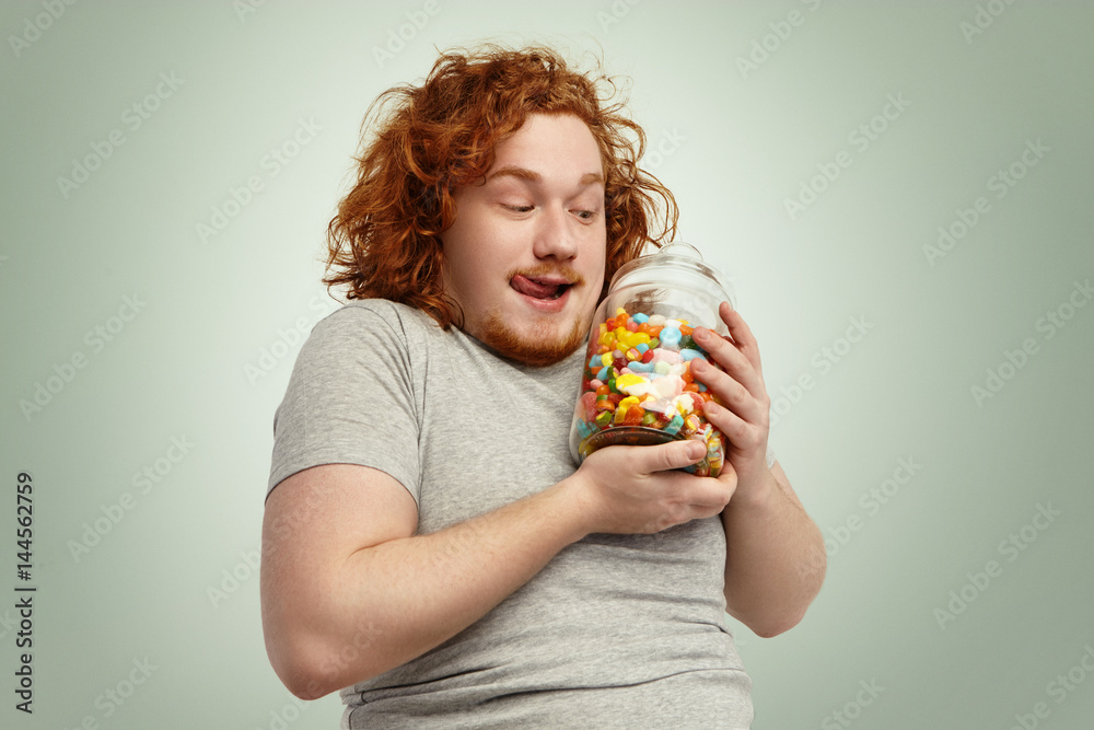 Yummy! Excited funny plump man holding glass jar of sweets and ...