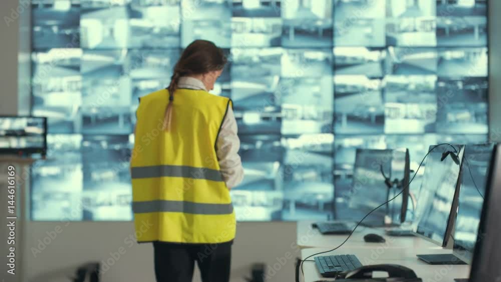Female surveillance officer watching the screens in observation control ...
