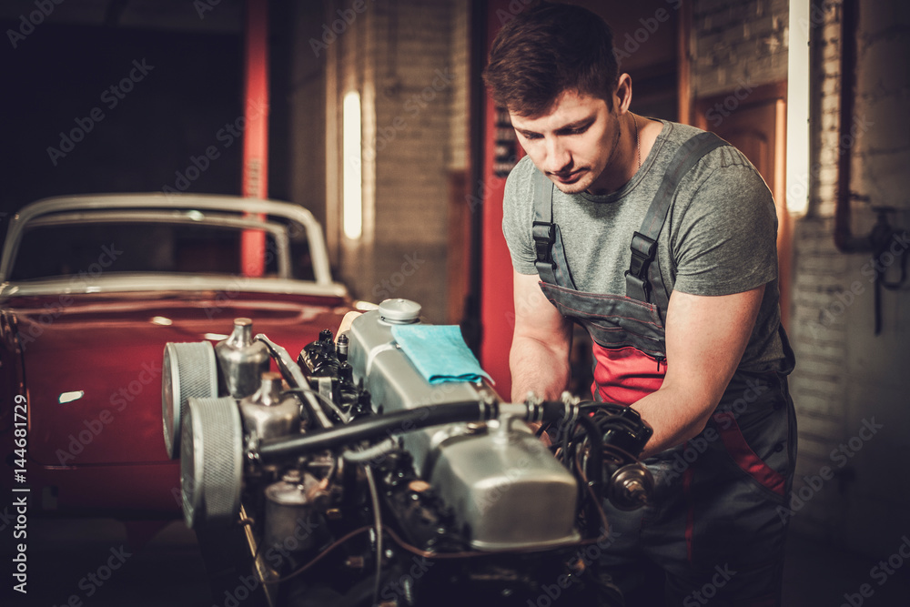 Mechanic working on classic car engine in restoration workshop Stock ...