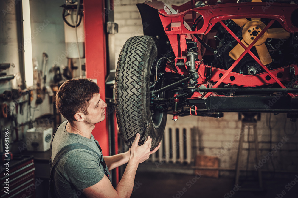 Mechanic working on classic car wheels and suspension in restoration ...