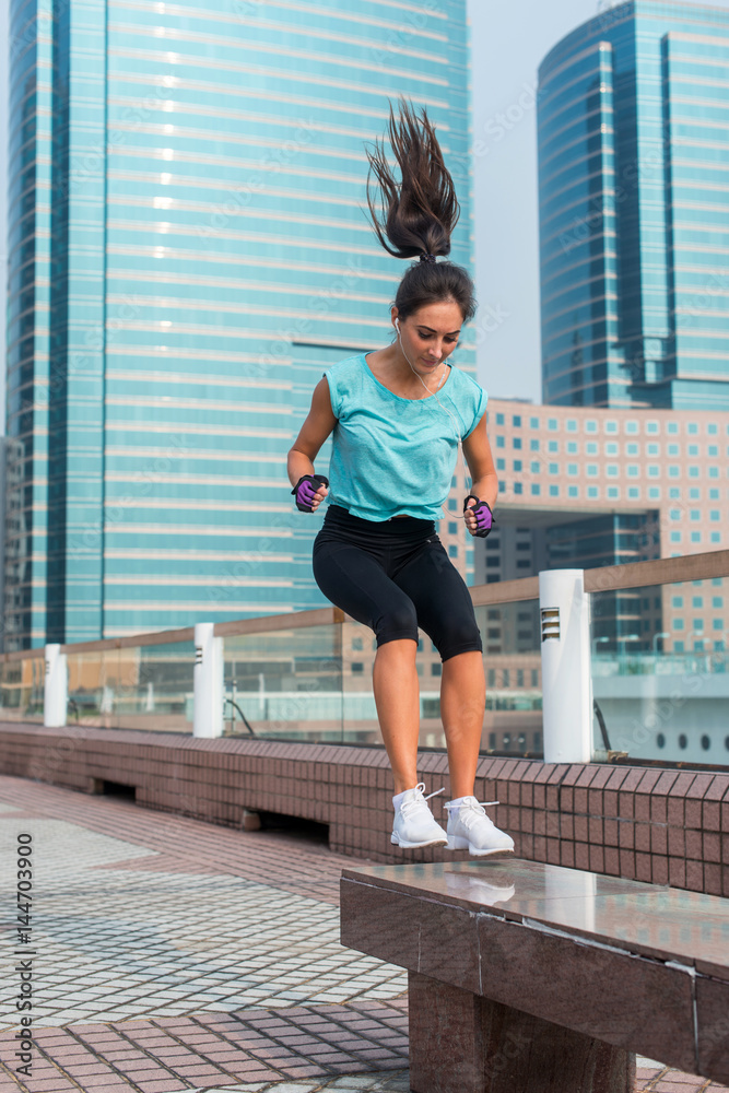 Young fit active woman bench jump squat jumping on city street. Fitness ...