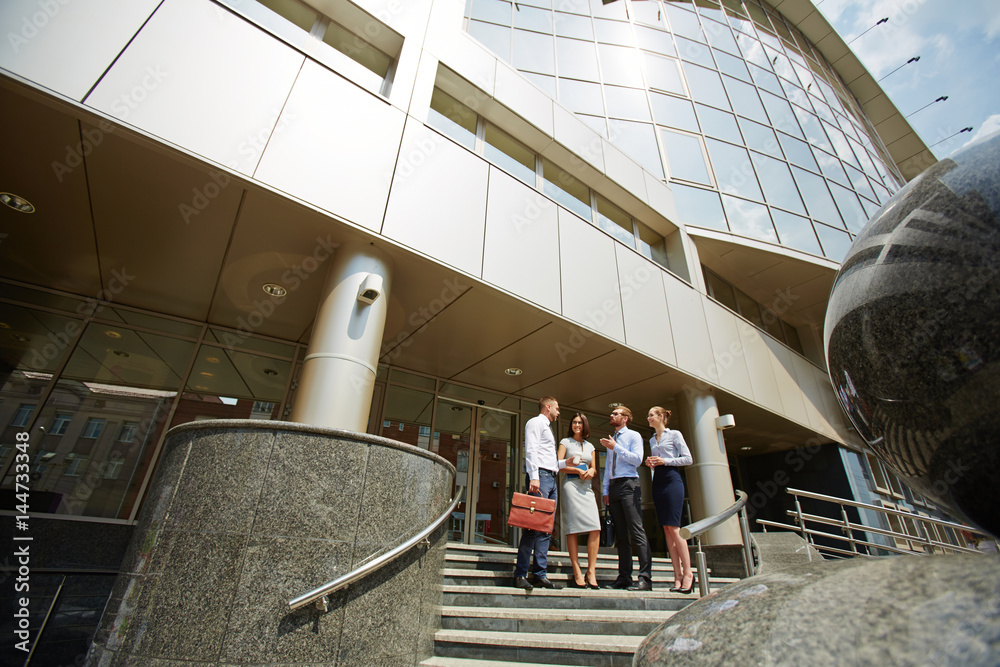 Wide angle shot, group of business people standing on steps of modern ...