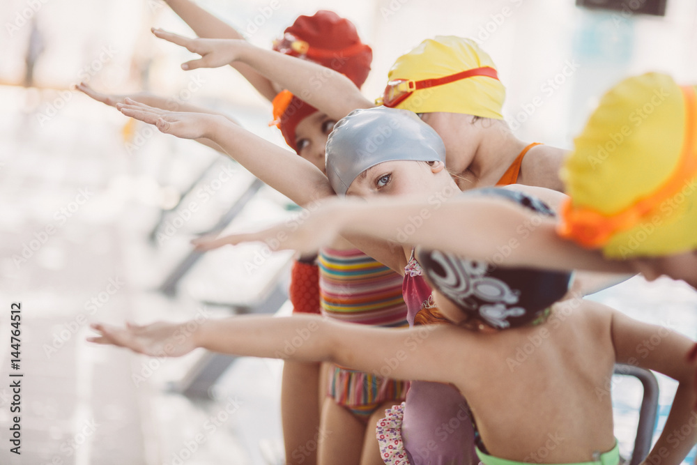 Instructor and group of children doing exercises near a swimming pool ...