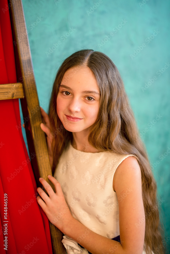 Рretty girl standing with your hands on the decorative ladder on a ...