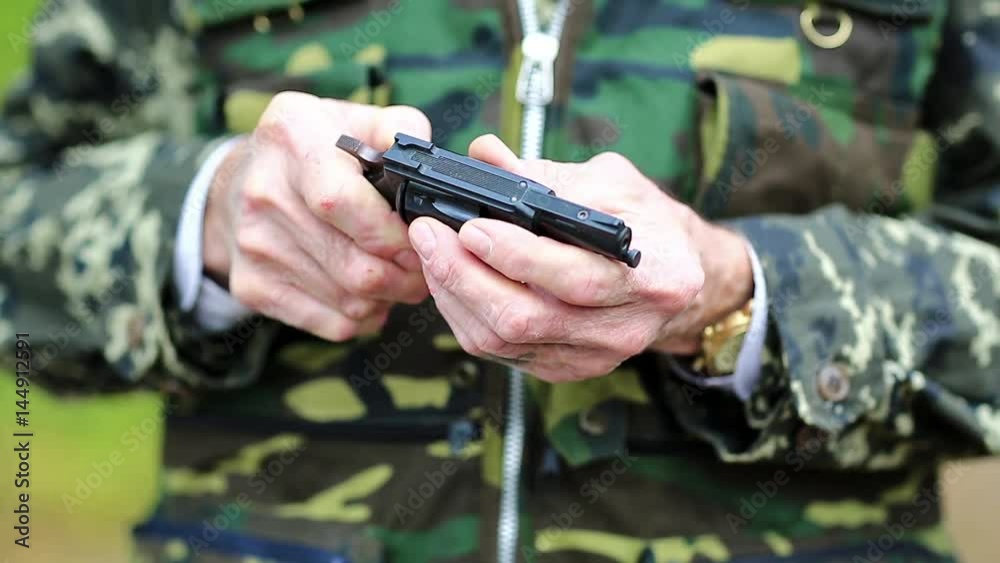 Man with black gun. Man in military uniform checks his revolver ...