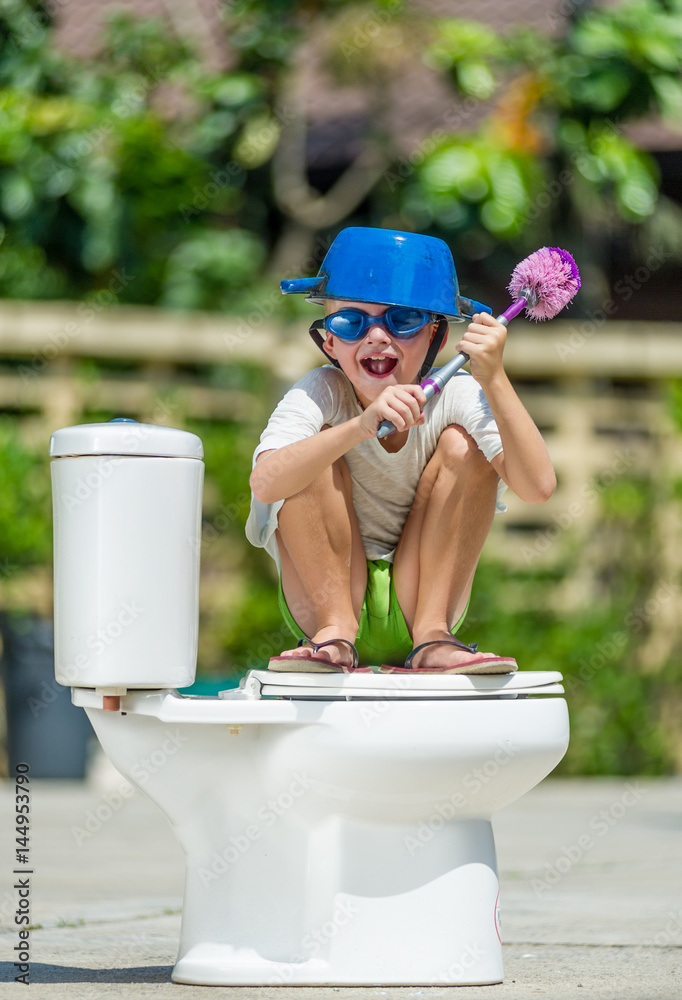Absurd picture: cute boy in goggles sitting on the toilet, which is ...