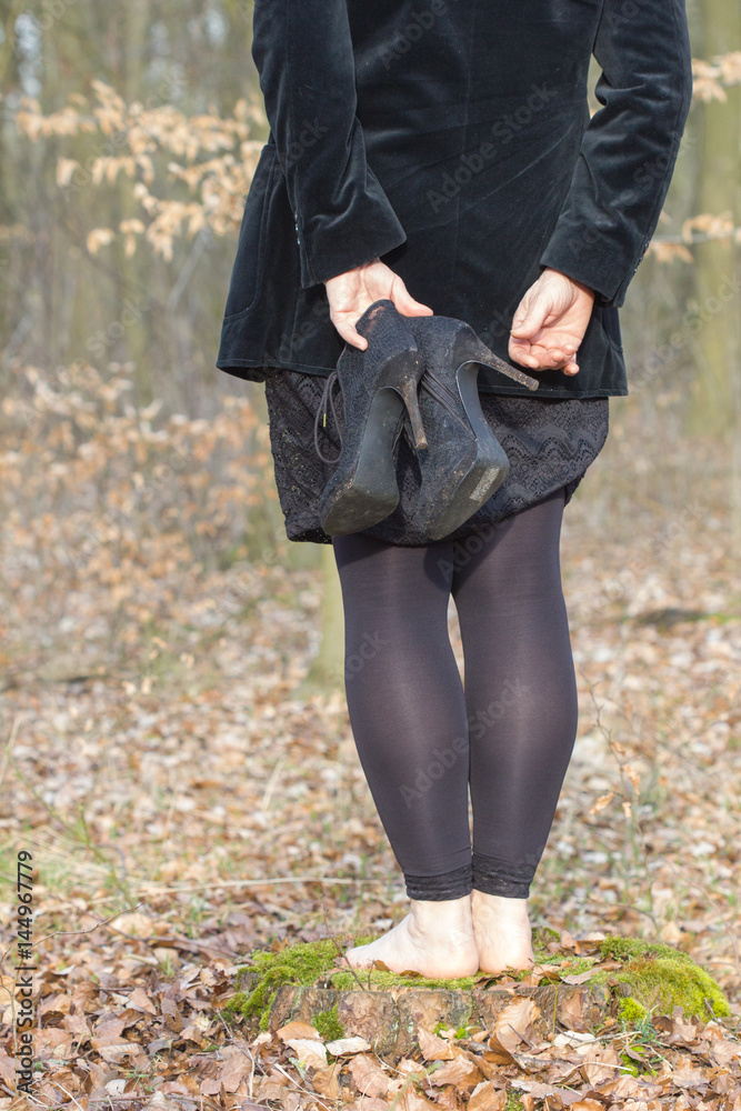 barefoot in the forest / A woman has pulled out her hoes shoes in the ...