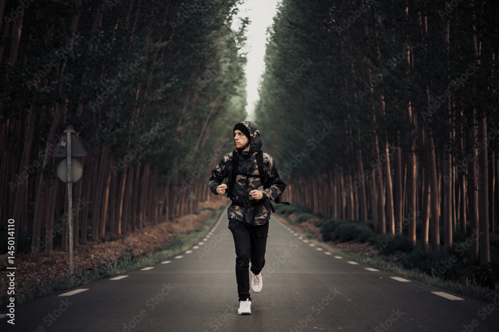 Backpacker man running on a forest road Stock Photo | Adobe Stock