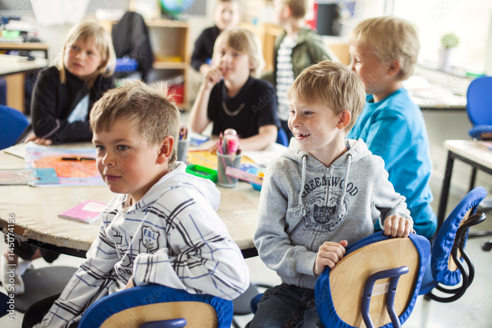 Schoolchildren sitting around table in classroom Stock Photo | Adobe Stock