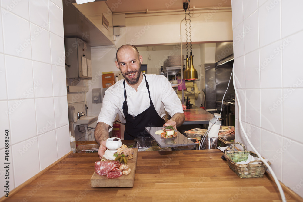 Happy chef serving food at commercial kitchen counter Stock Photo ...