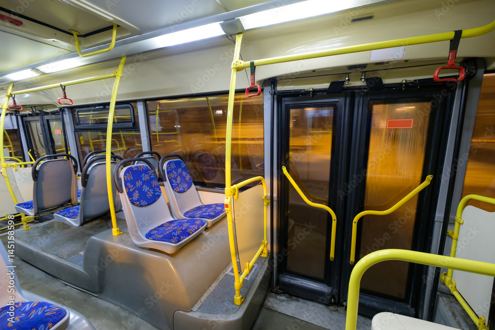 Interior of modern city bus with seats, doors and handles in night ...