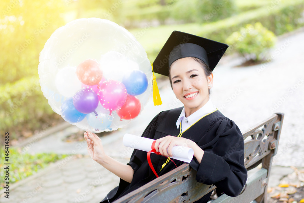 Portrait of happy young female graduates in academic dress and square ...