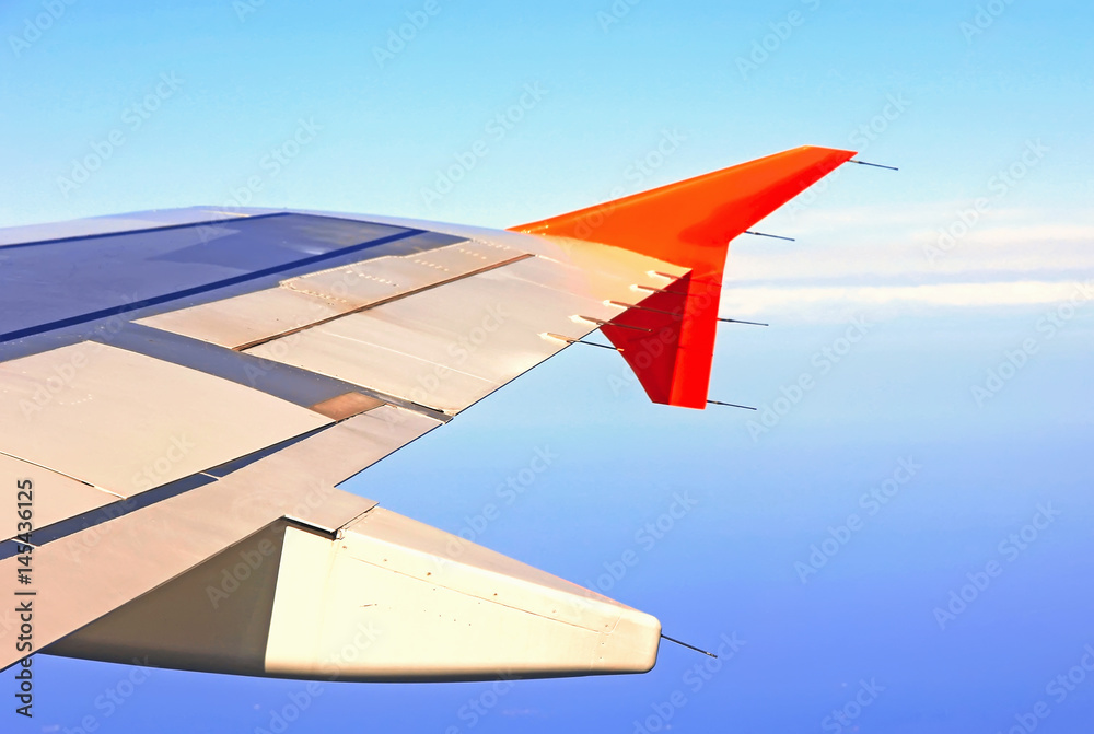 Aircraft wing in flight, view from the window at the blue sky airplane ...