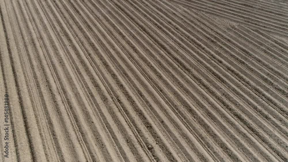 Aerial footage above rural farming land showing fresh soil prepared by ...