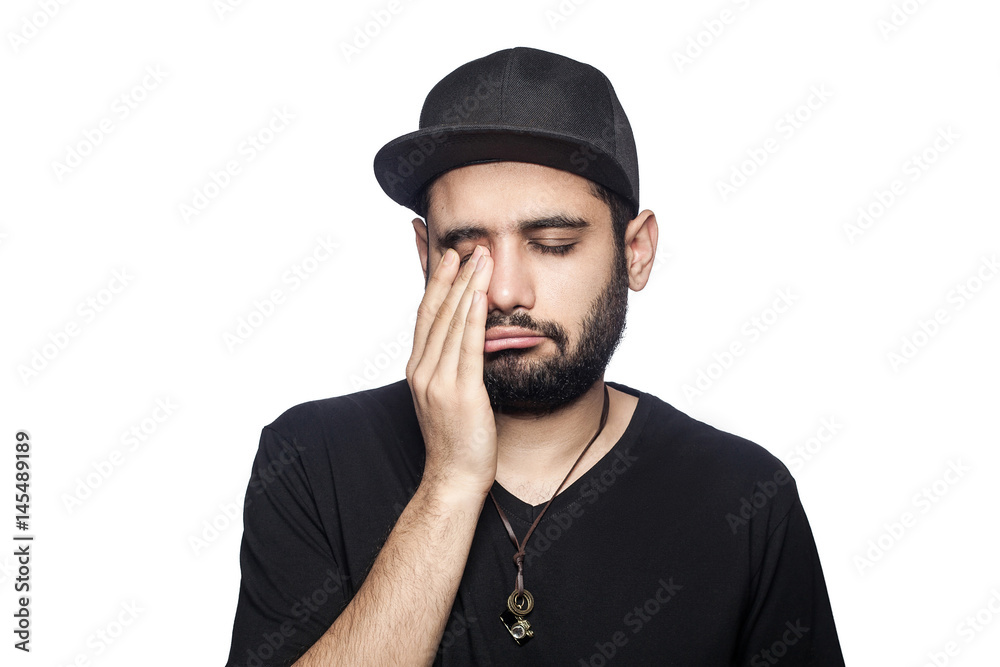Portrait of young unhappy sad man with black t-shirt and cap looking at ...