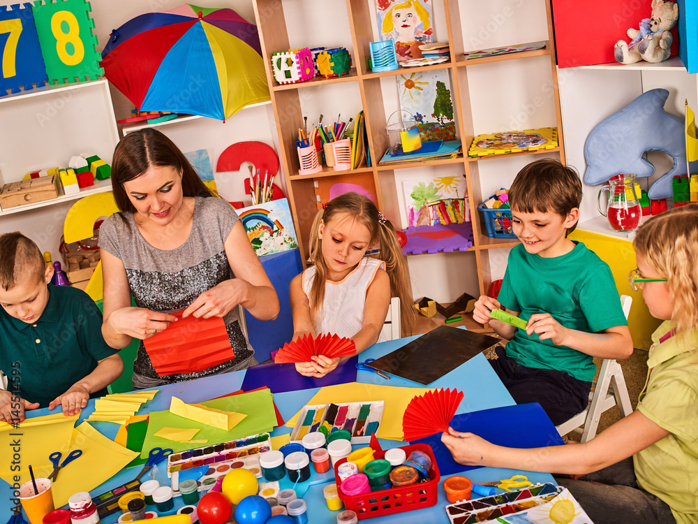 School children with scissors in kids hands cutting paper with teacher ...